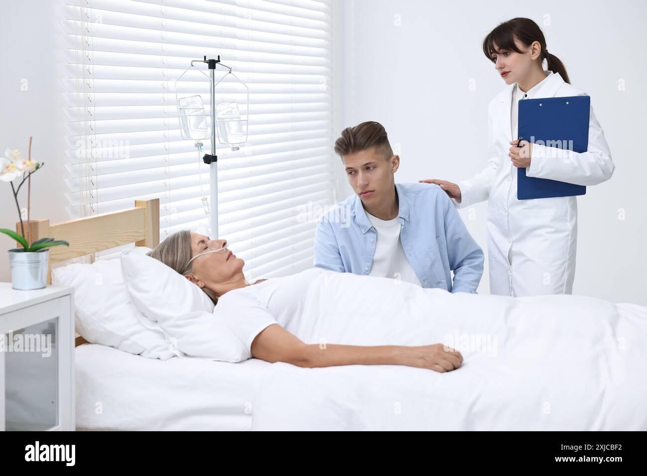 Coma patient. Sad young man near his unconscious mother talking with ...