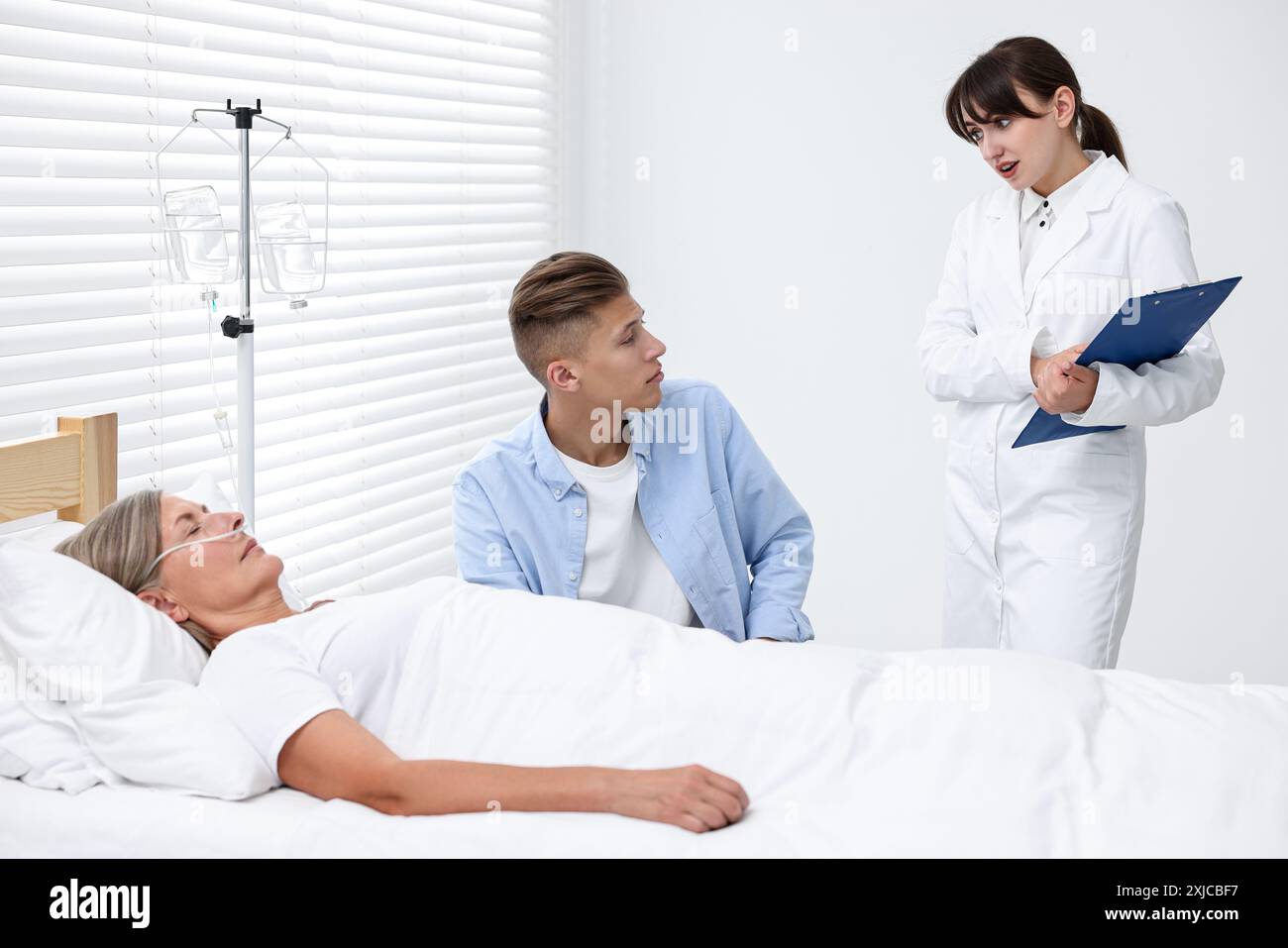 Coma patient. Sad young man near his unconscious mother talking with ...