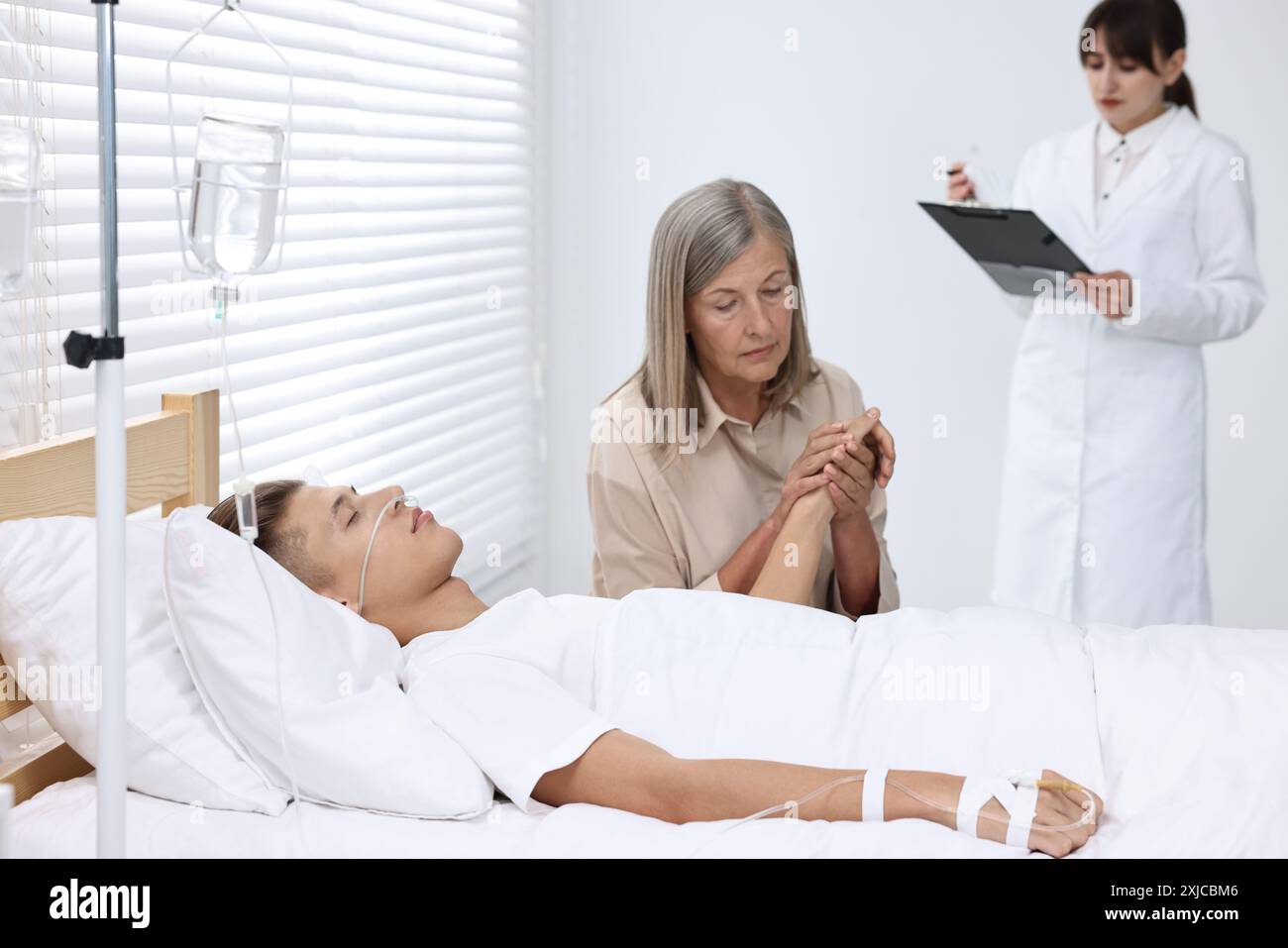 Coma patient. Sad mature woman near her unconscious son in hospital ...