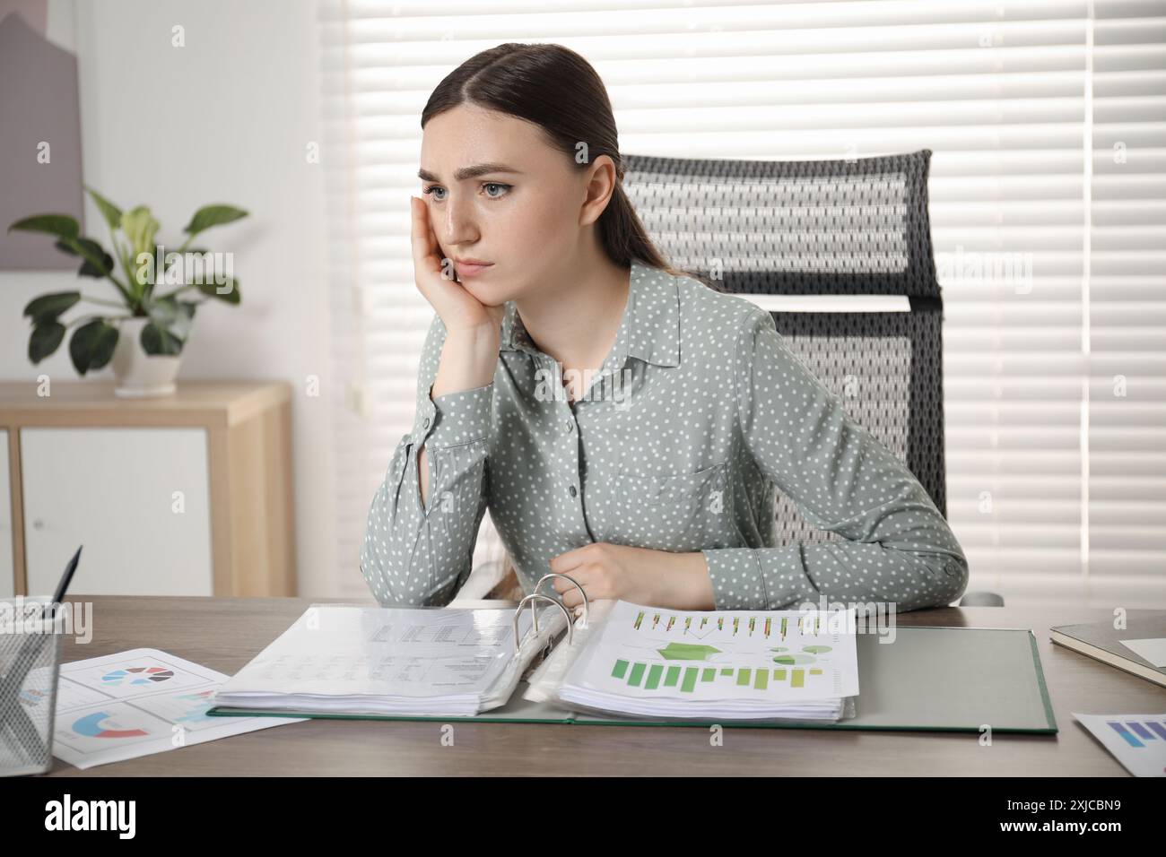 Embarrassed woman at wooden table with documents in office Stock Photo ...