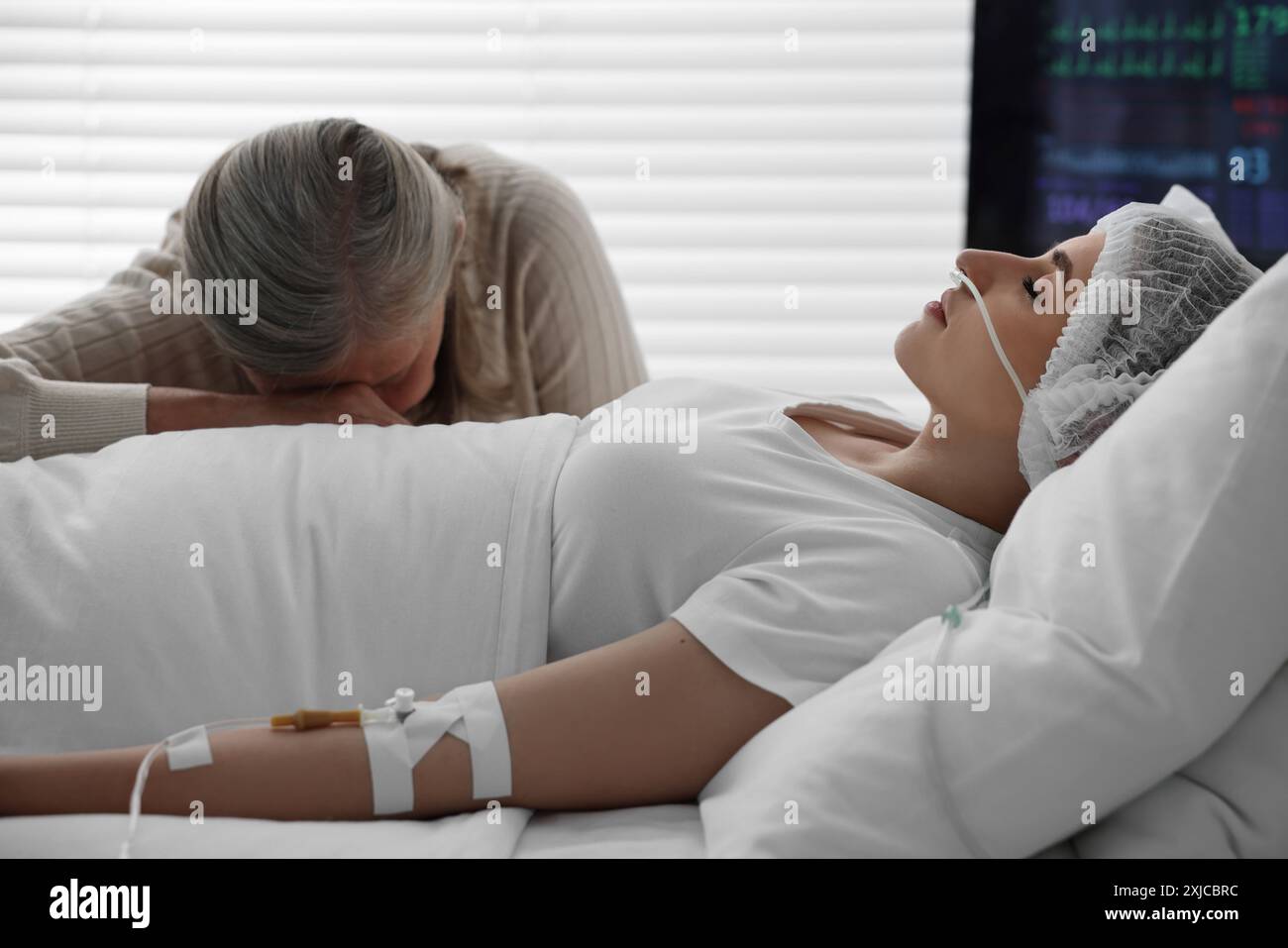Coma patient. Sad mature woman near her unconscious daughter in ...