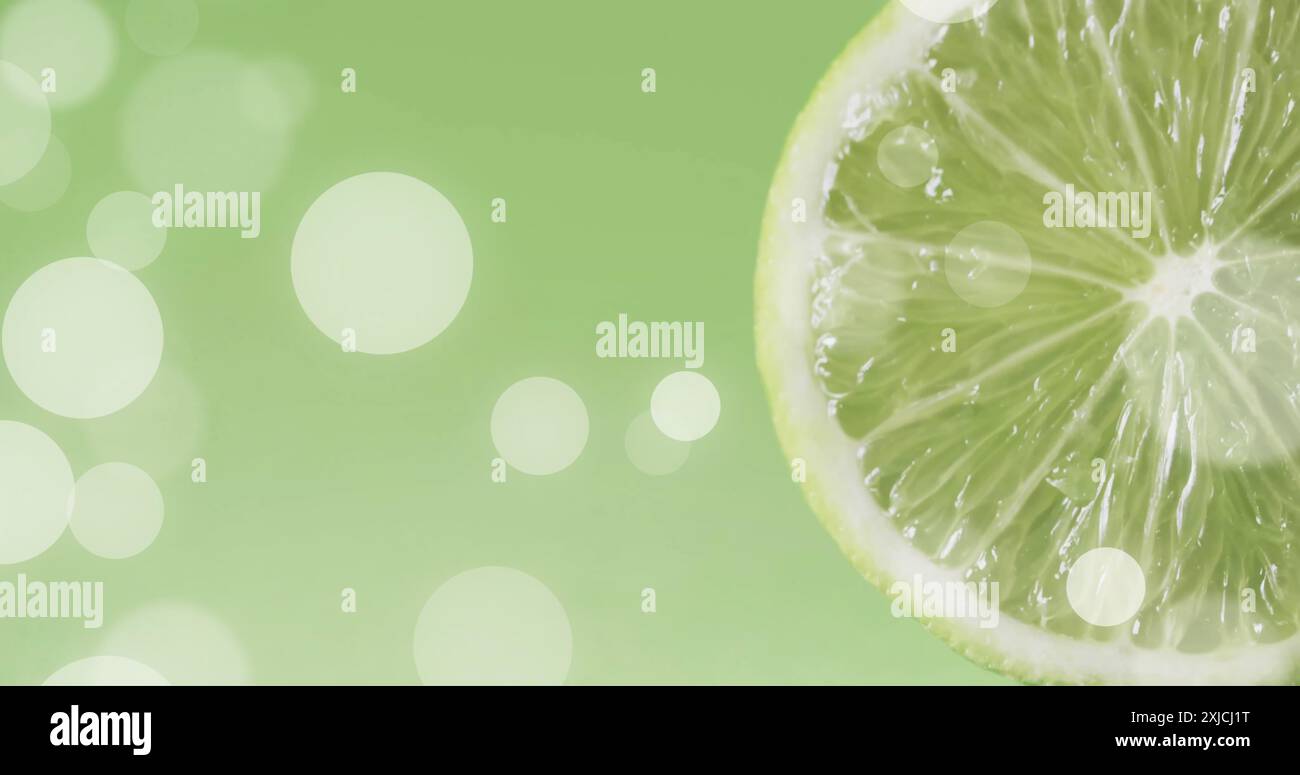Composition of halved lime and white spots on green background Stock ...