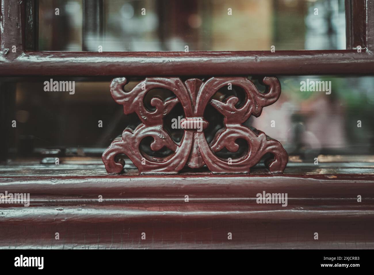 A close-up view of an ornate, maroon wooden window frame with intricate ...