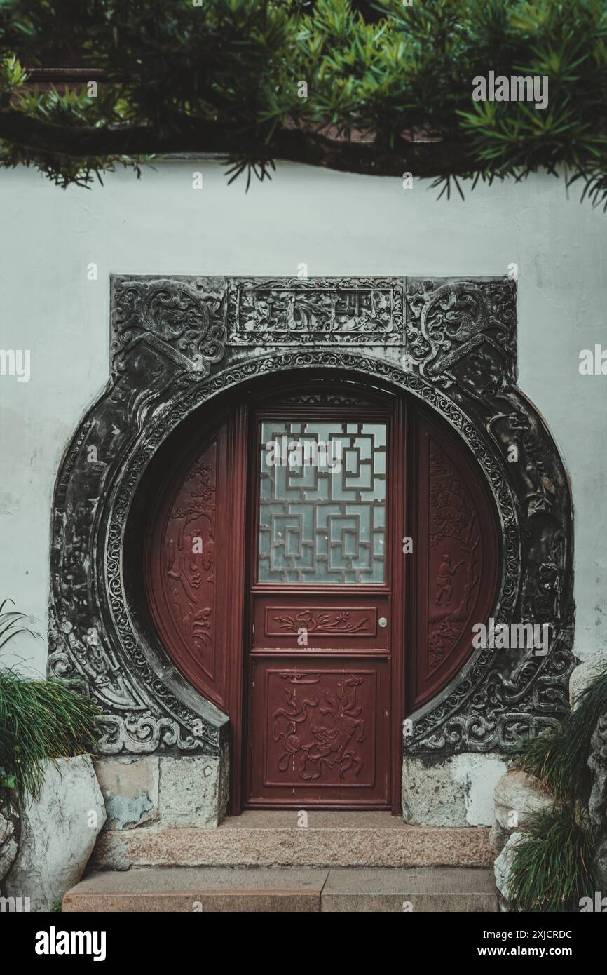 A traditional Chinese doorway with an ornate stone frame and a red ...