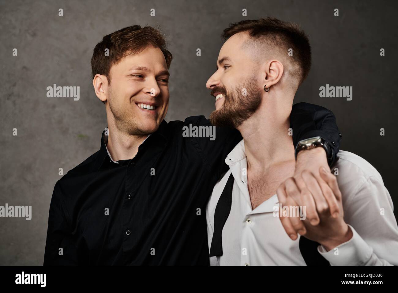 A portrait of two men in suits, smiling and looking at each other ...