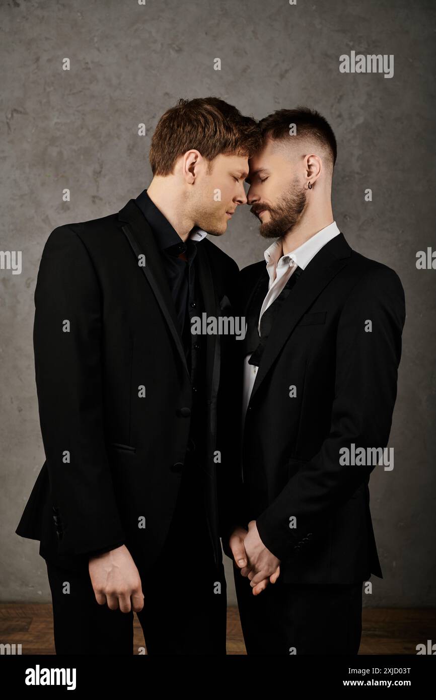 Two men in elegant suits embrace, their foreheads touching in a gesture ...