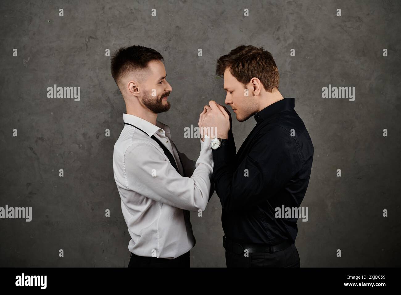 Two men in stylish suits share a tender moment, their hands clasped ...
