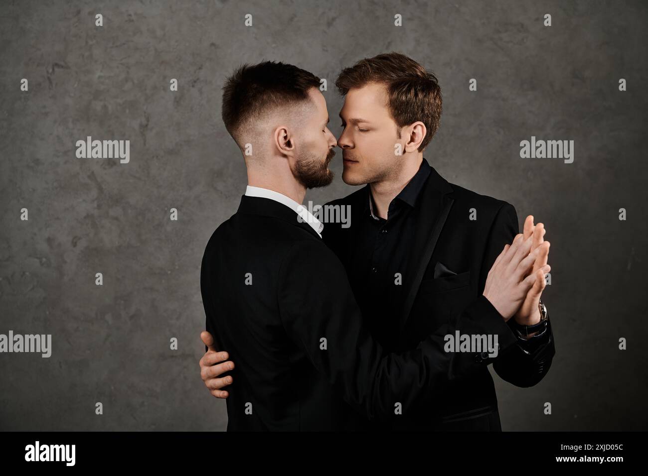 Two men in black suits stand close together, embracing and looking ...