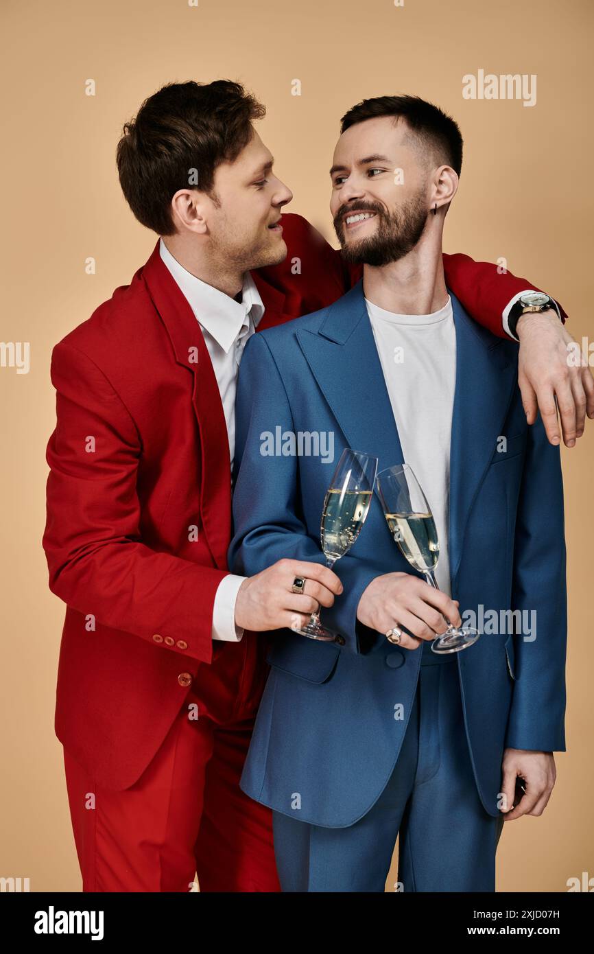 Two men in suits, one red and one blue, hold champagne glasses and look ...