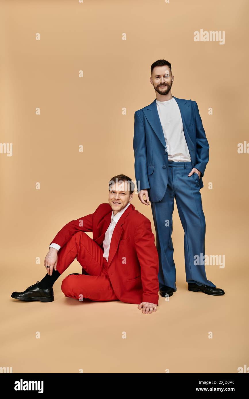 Two men in suits pose for a photograph, one standing and one sitting ...