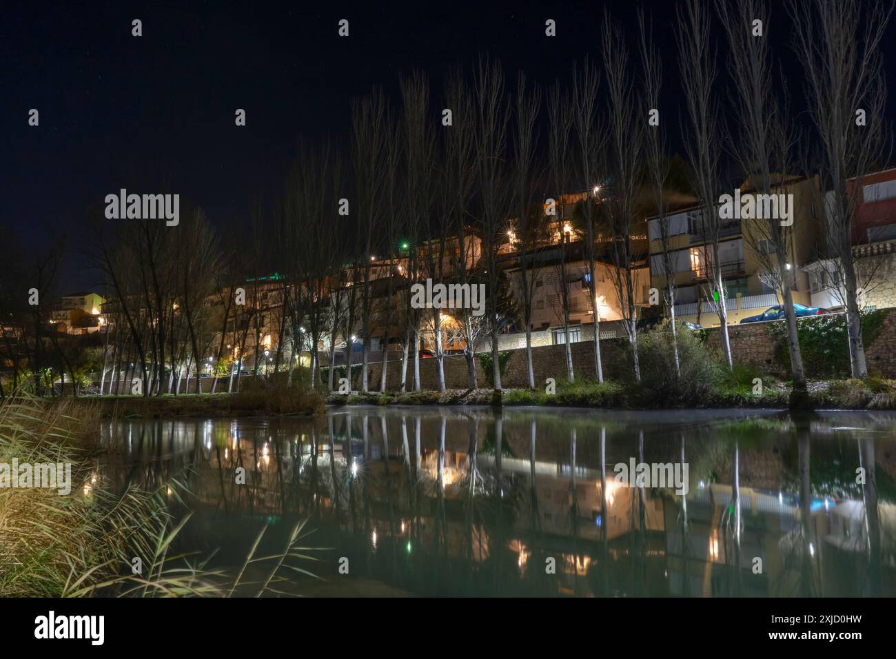Night view of a riverside town with illuminated buildings reflecting on ...