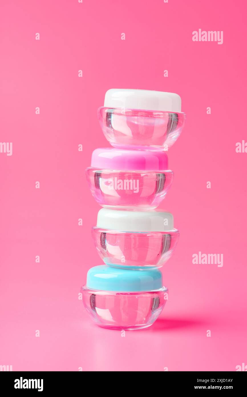 Stacked Clear Plastic Containers With Colored Lids on Pink Background ...