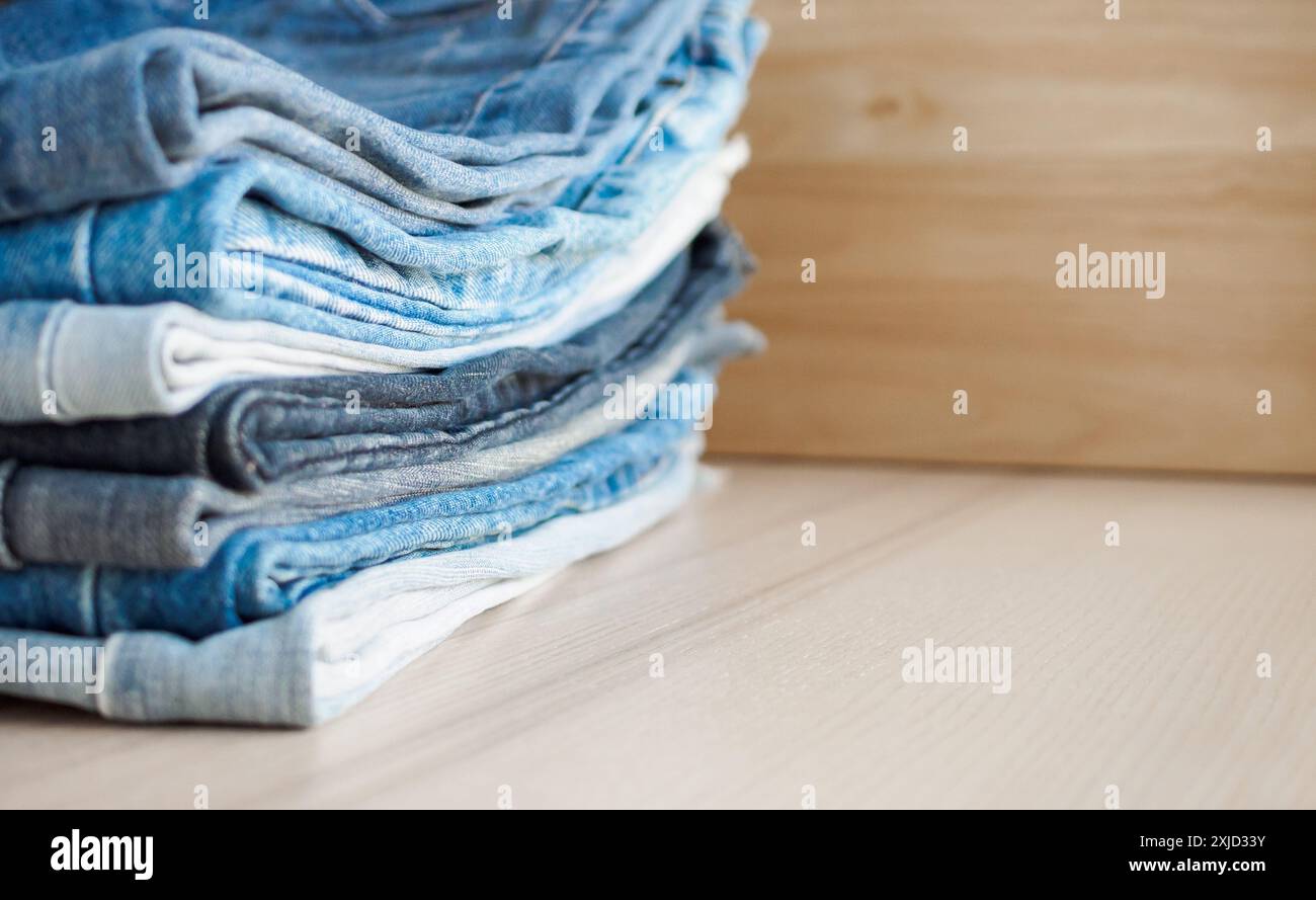 denim blue jeans stack on wood table background Stock Photo - Alamy