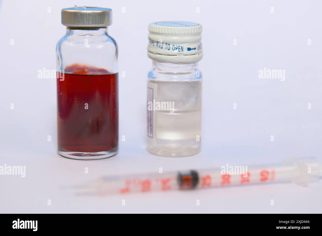 Two glass bottles containing clear and colored liquids with a plastic ...