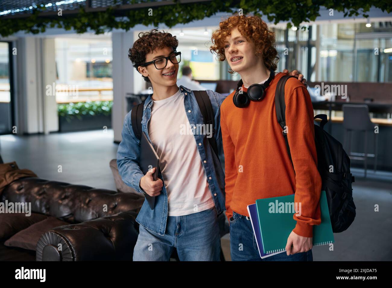 Two positive boys walking in coworking office together Stock Photo - Alamy