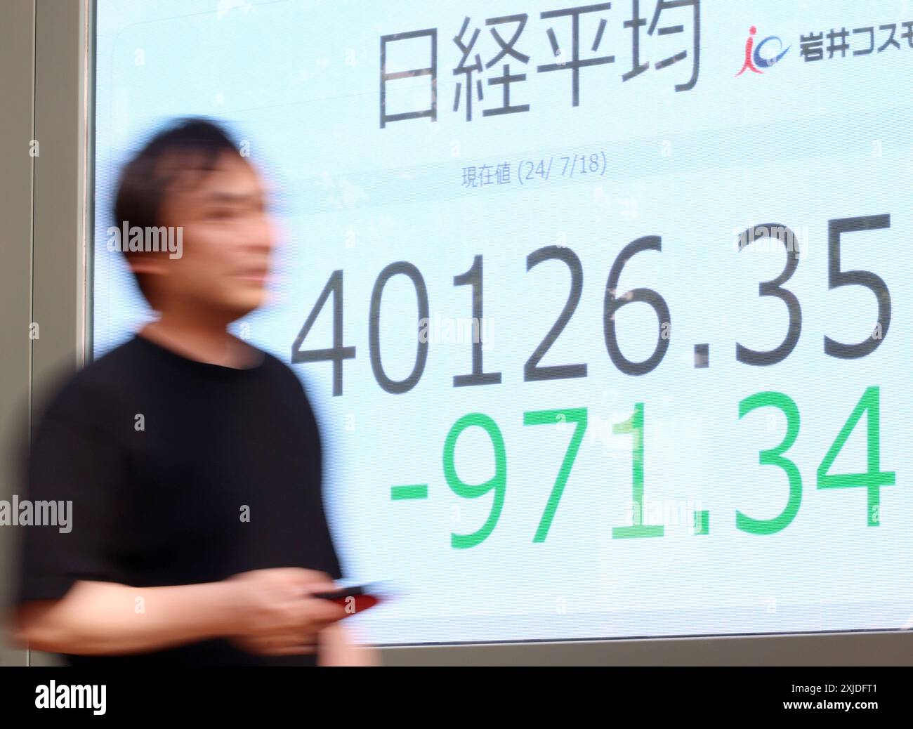 Tokyo, Japan. 18th July, 2024. A pedestrian passes before a share ...