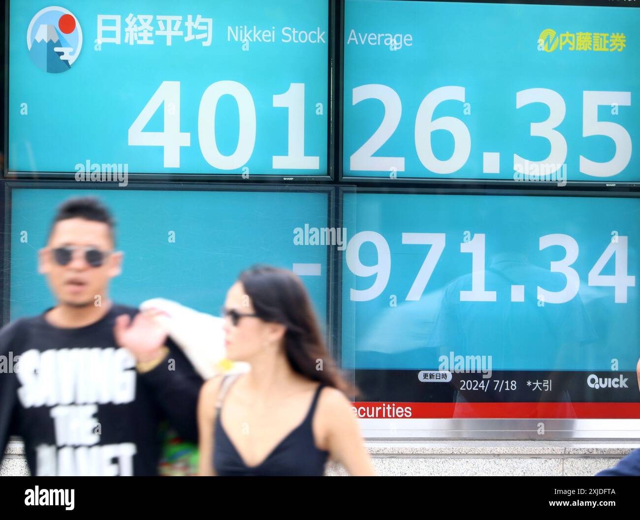 Tokyo, Japan. 18th July, 2024. Pedestrians pass before a share prices ...