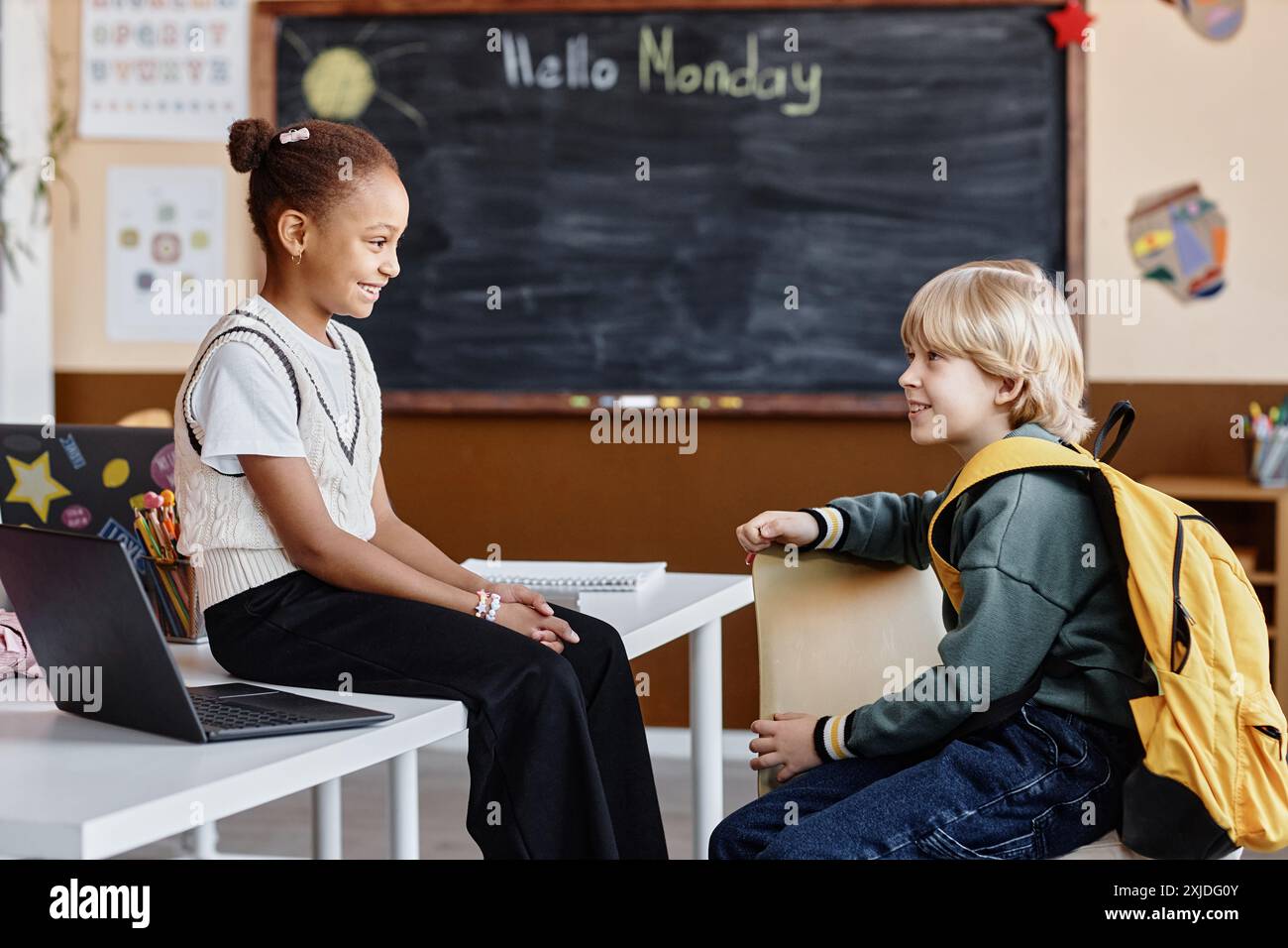 Side view of two diverse smiling kids communicating on break against ...