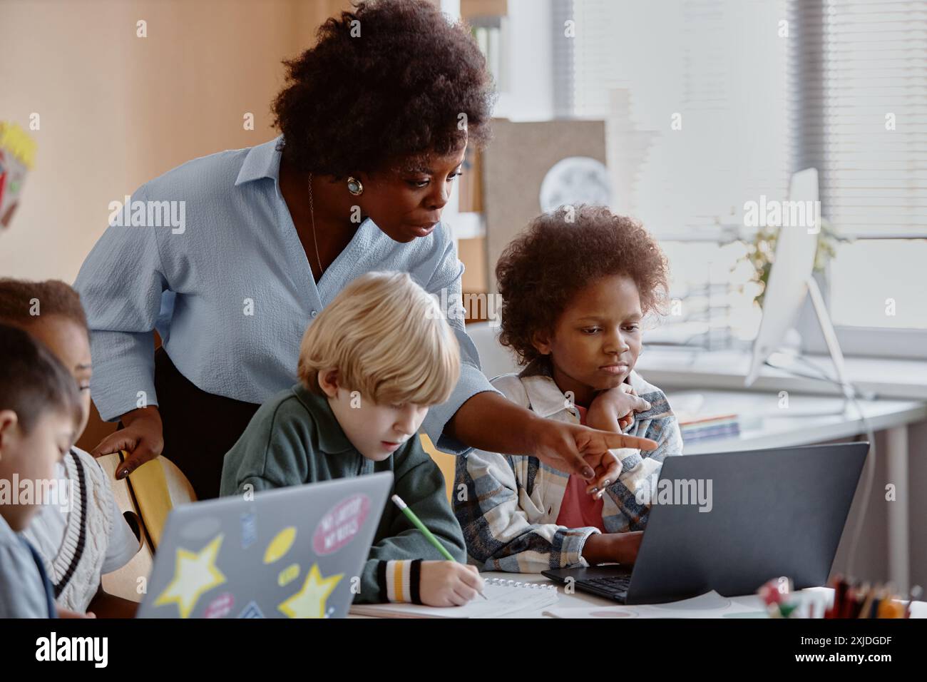 Young female teacher of Black ethnicity explaining new topic to girl ...