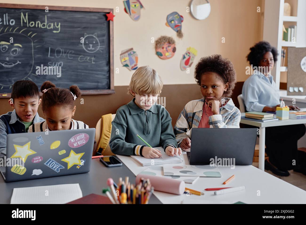 Shot of multiethnic group of children studying in pairs at large desk ...