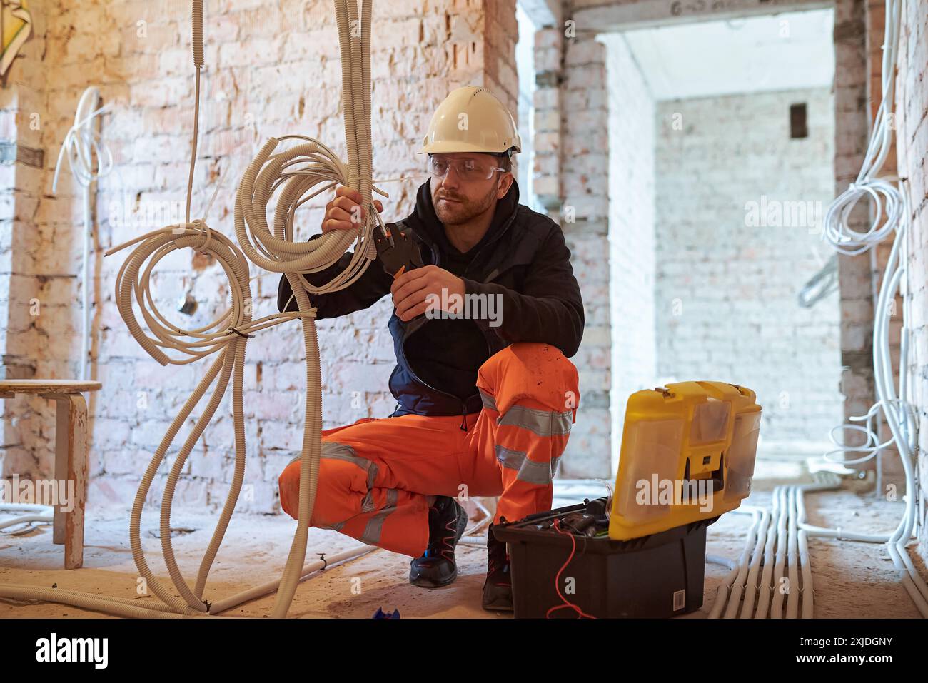 Male electrical contractor working with multiple cables during ...