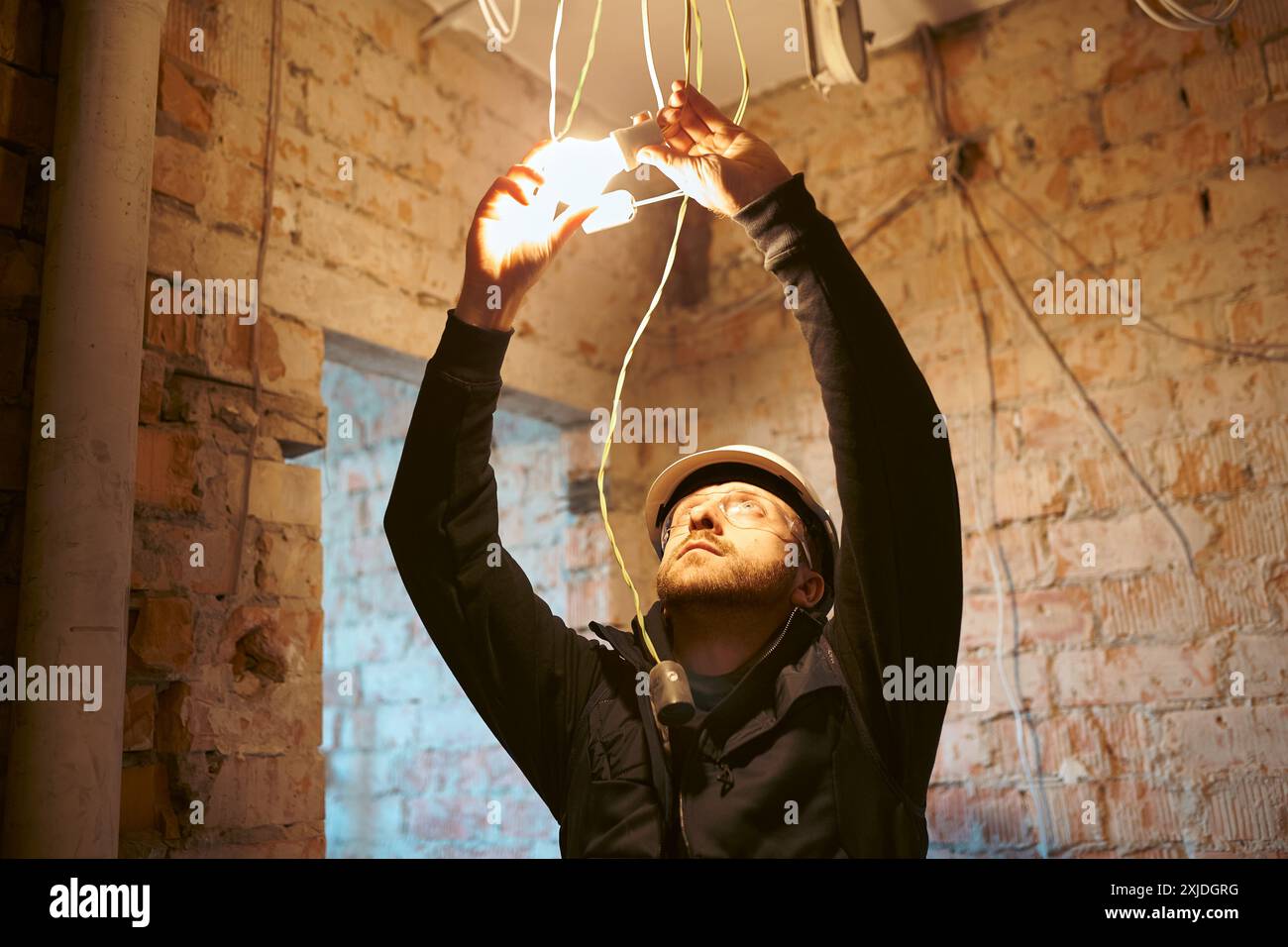 Male construction worker installing temporary light bulb on site Stock ...