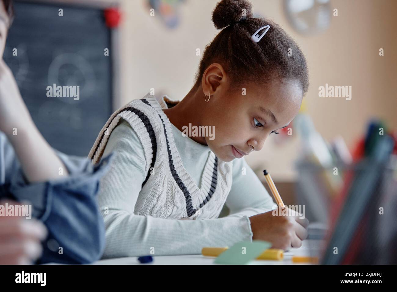 Side view portrait of studious young girl of primary school writing ...