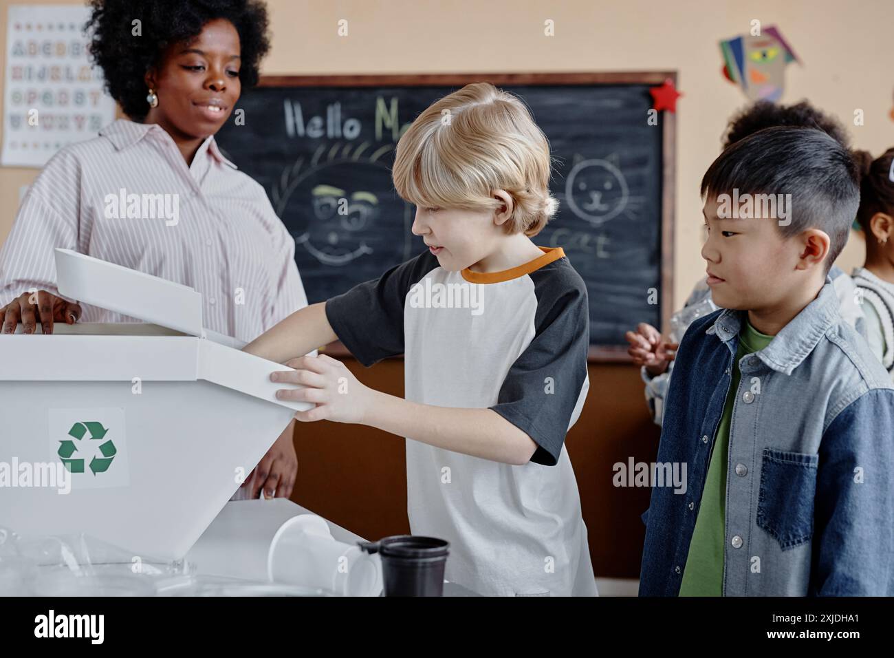 Side view of young boy putting recyclable in waste sorting bin during ...