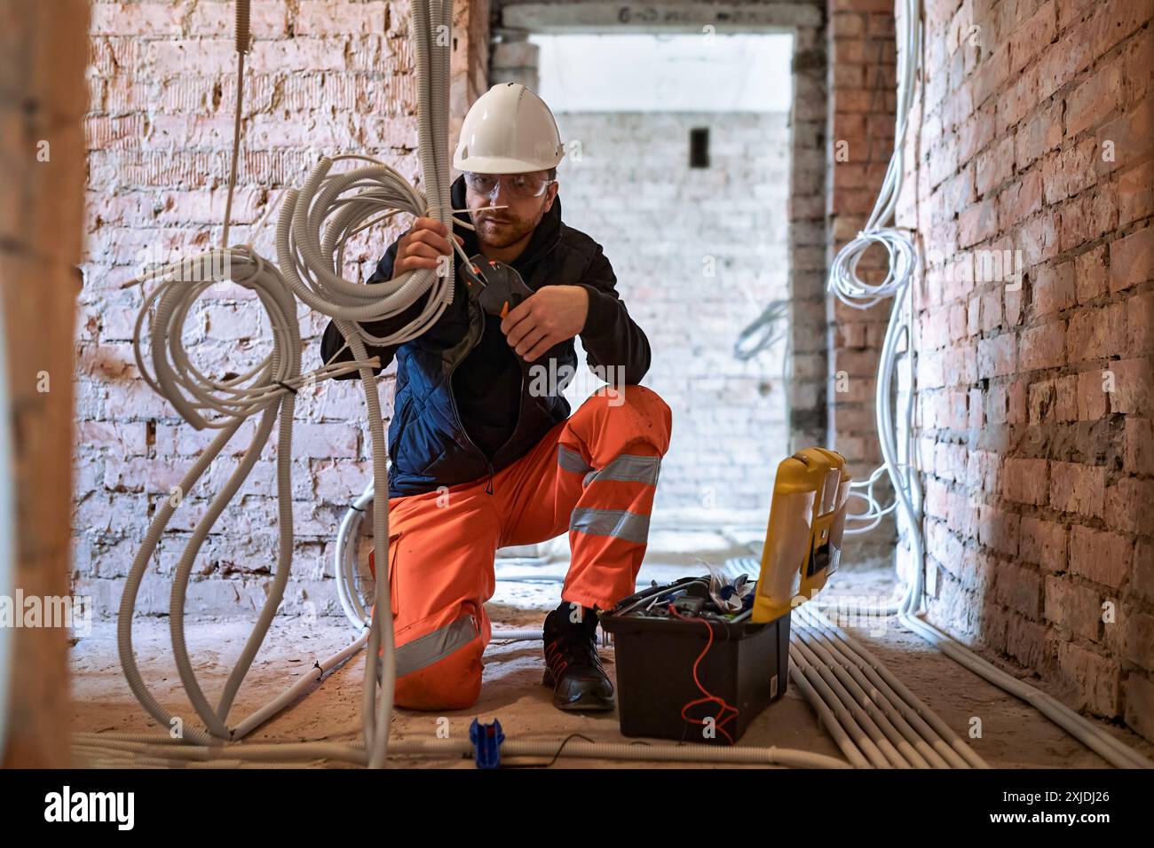 Male electrical contractor working with multiple cables during ...