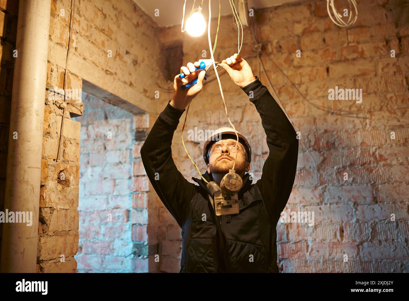 Male construction worker installing temporary light bulb on building ...