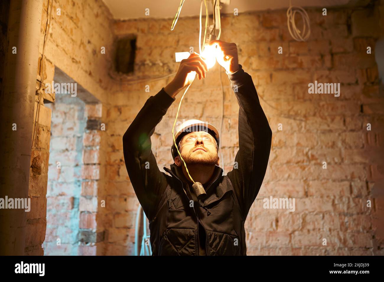 Male construction worker installing temporary light bulb on building ...