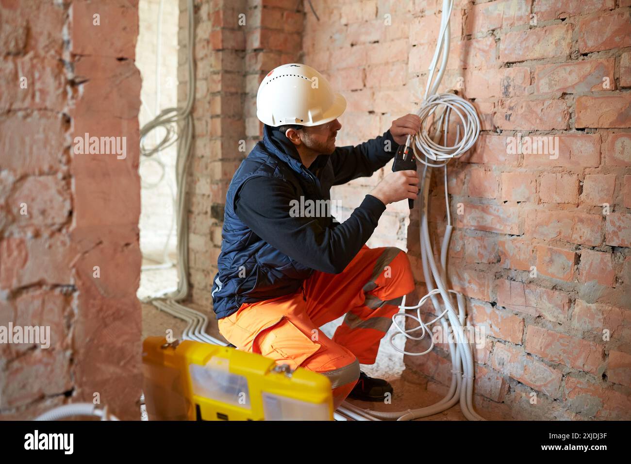 Male electrical contractor working with multiple cables during ...
