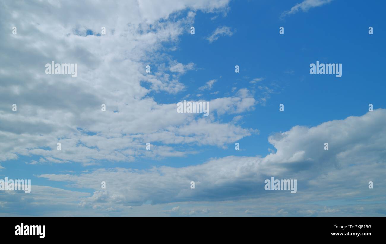 Time lapse. White and gray clouds fly across the sky and change shape ...