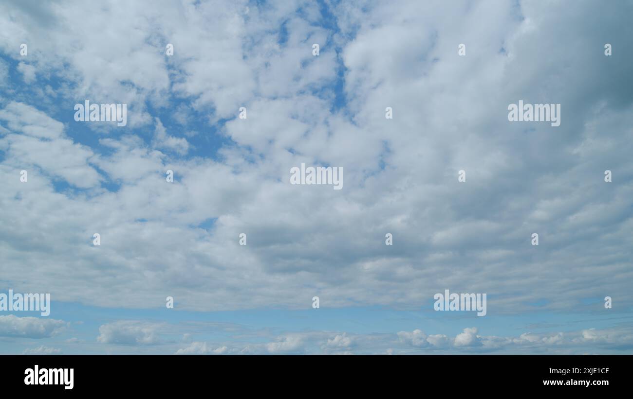 Time lapse. White and gray clouds fly across the sky and change shape ...