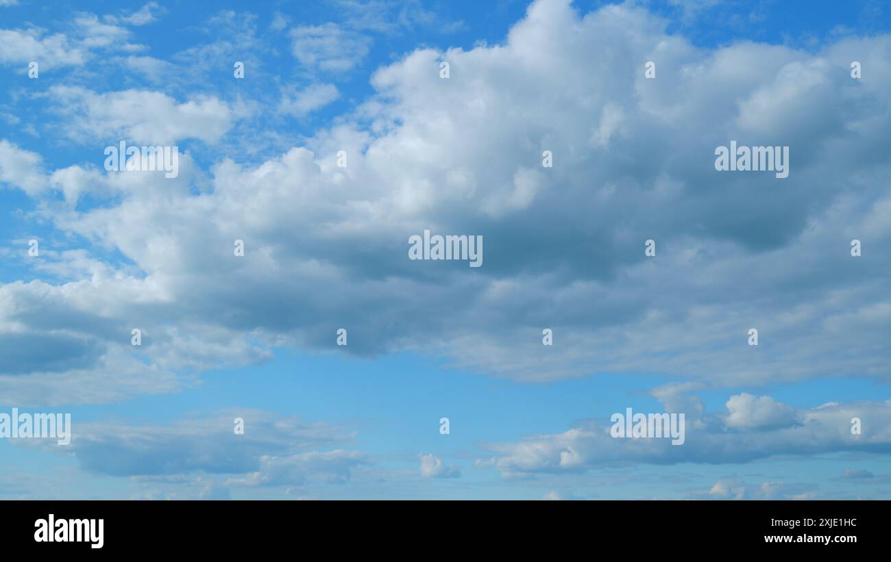 Time lapse. White and gray clouds fly across the sky and change shape ...
