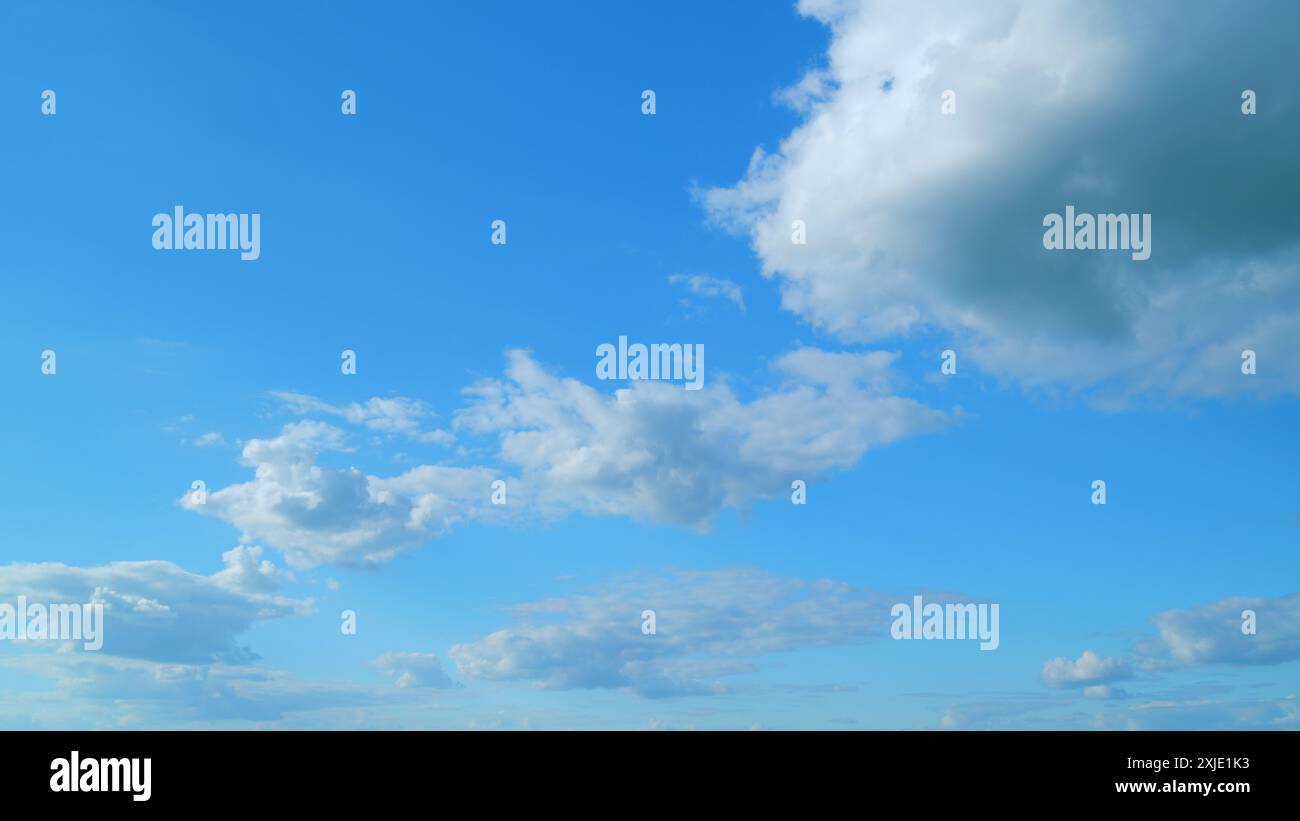 Time lapse. Clouds running across the blue sky. White puffy and fluffy ...