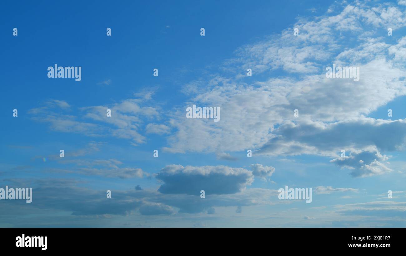 Time lapse. White and gray clouds fly across the sky and change shape ...