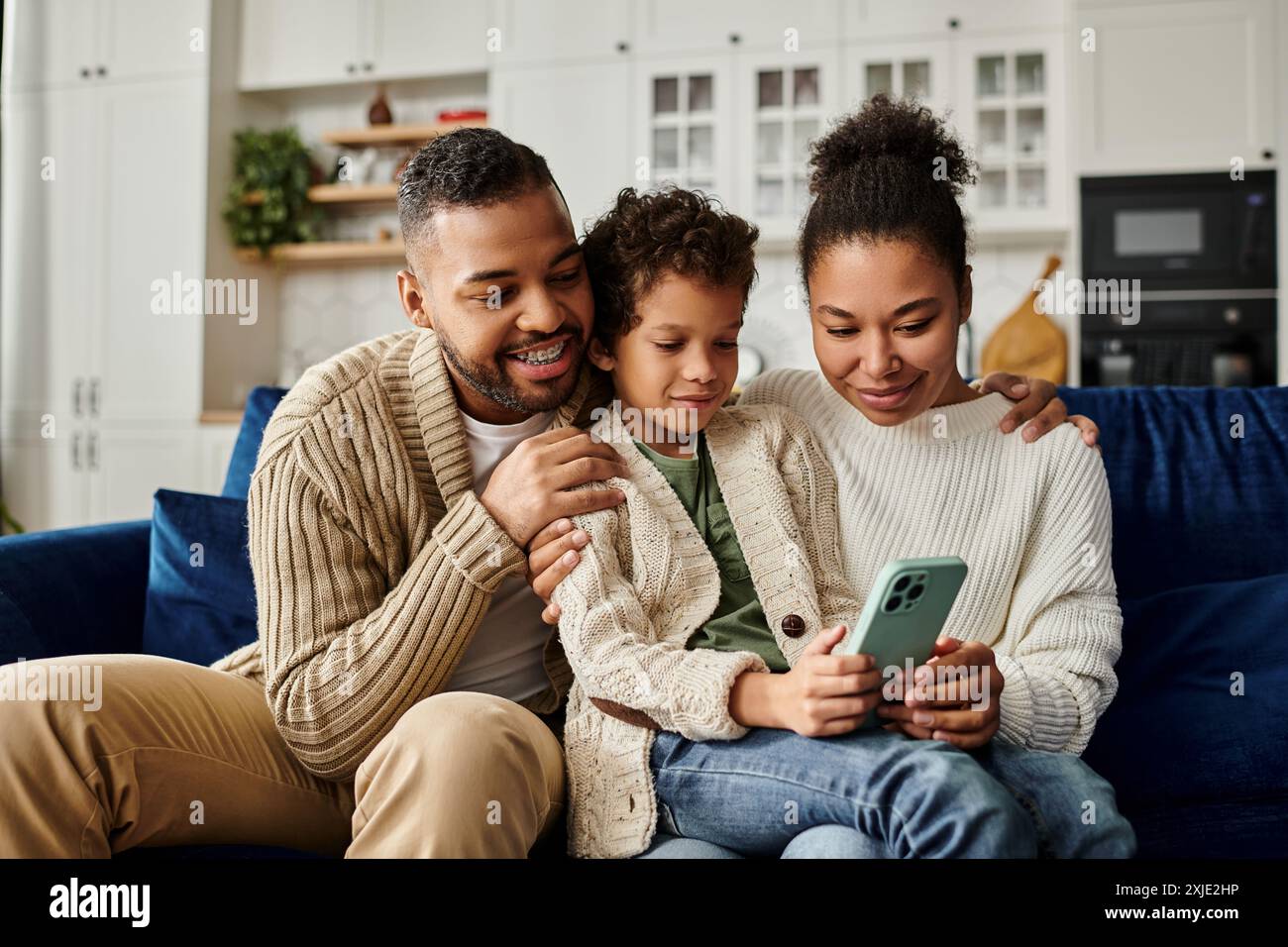 African American family bonding on a couch, all focused on a cell phone ...