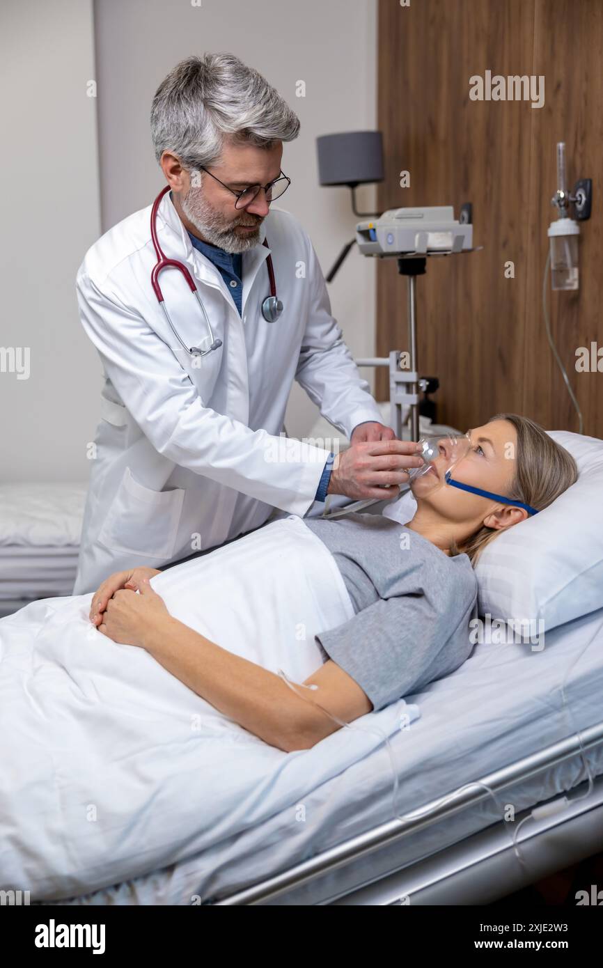 Doctor fixing oxygen mask on a female patient face in clinic Stock ...
