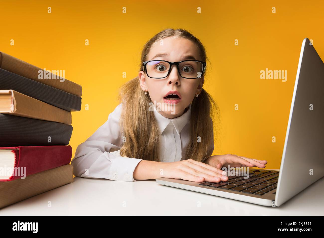 Surprised First-Grade Schoolgirl Doing Homework On Laptop, Yellow ...