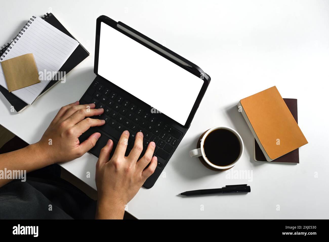 Overhead view of young woman typing on wireless keyboard of digital ...