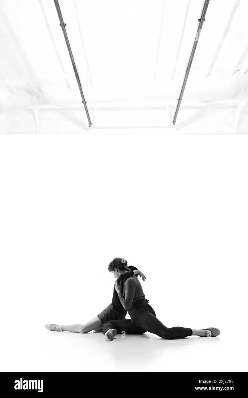Ballet partners in close embrace sitting on floor and shows connection ...