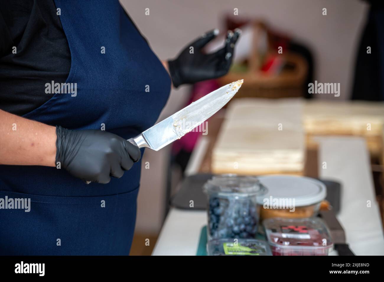 A baker holding a knife in a kitchen. Shallow depth of feld Stock Photo ...