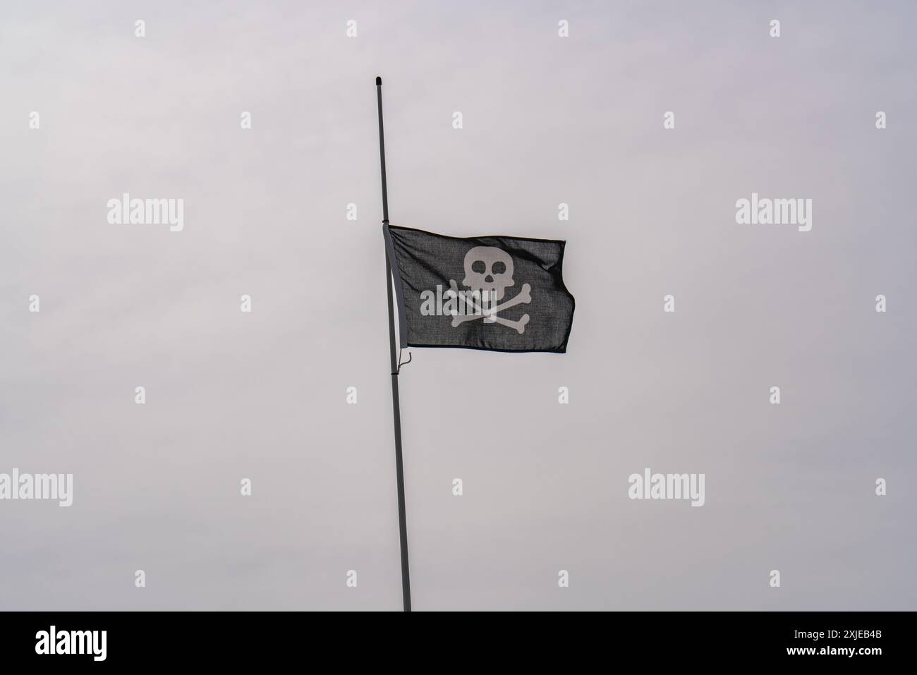 Pirate flag waving in the gray sky, skull and crossbones Stock Photo ...