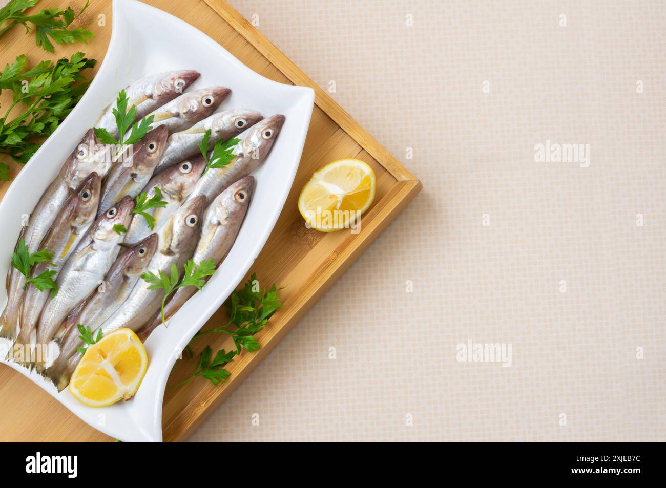 Fresh uncooked haddock fishes on in ceramic dish on table, raw whiting ...