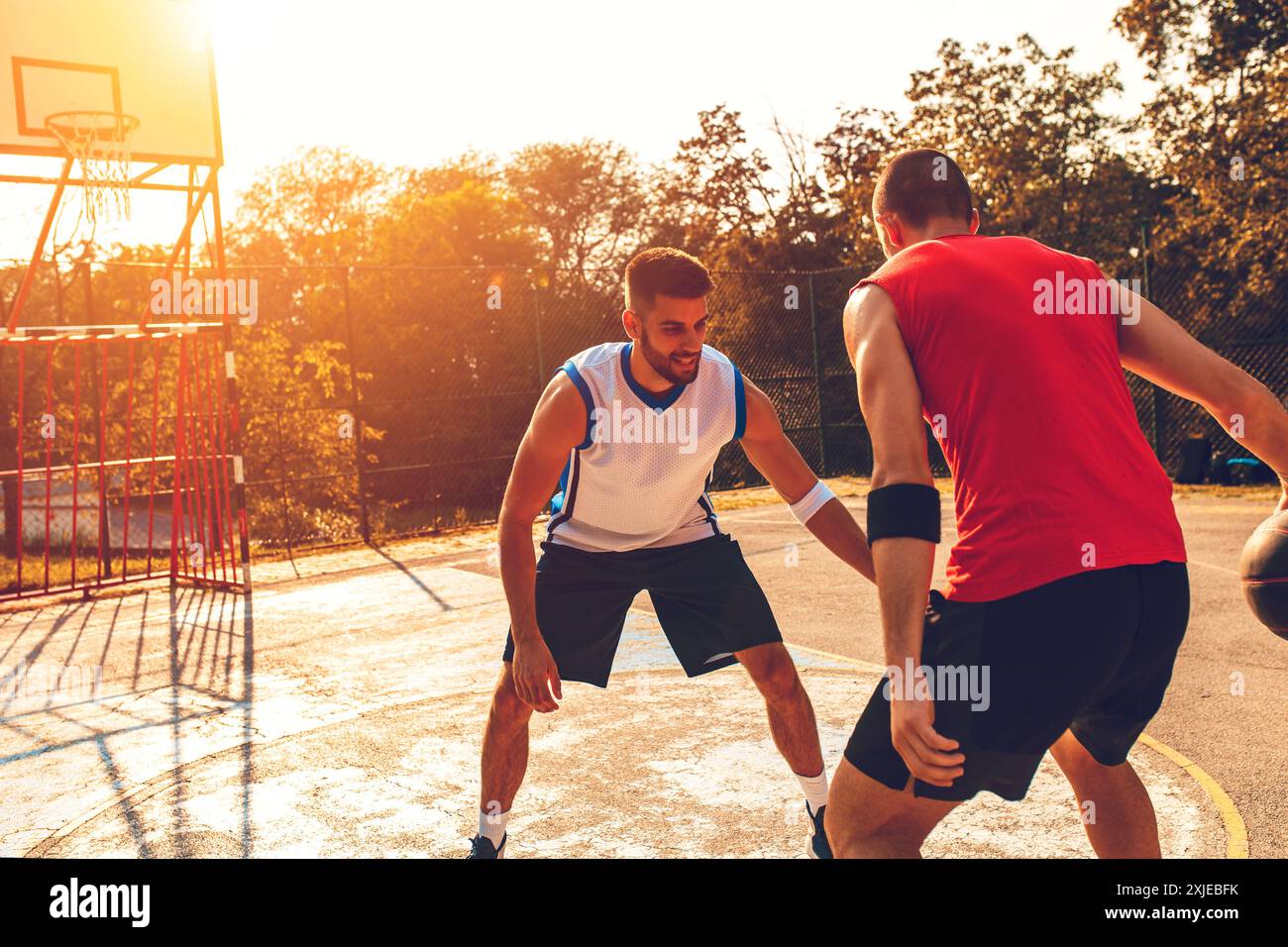 Two male friends playing basketball on court outdoors Stock Photo - Alamy