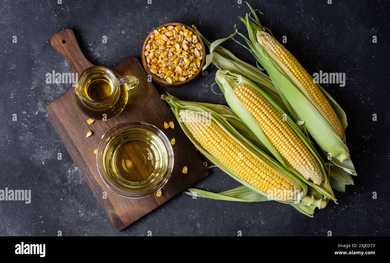 Corn oil in glass bowl with fresh ripe corn cobs on rustic table ...