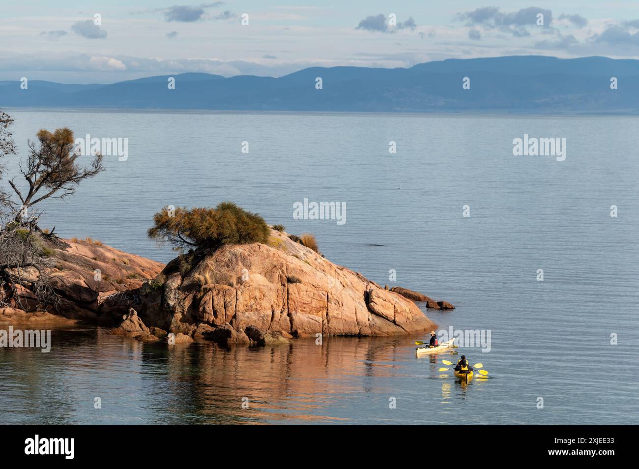 Two kayaks around a small rocky headland at a small peninsula bay ...