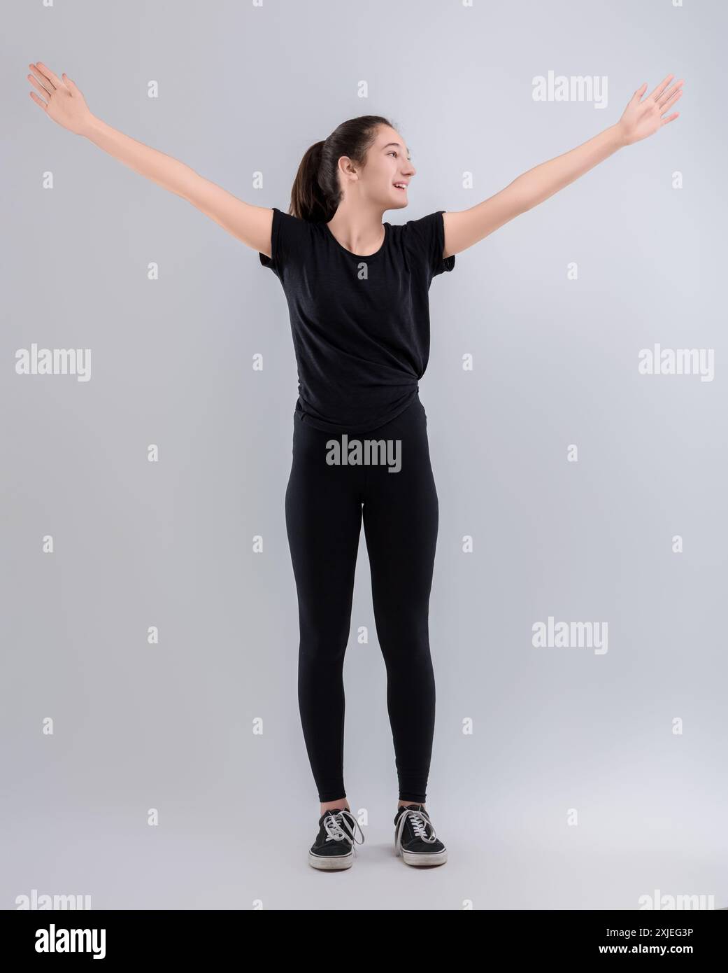 Confident young woman in black athletic clothes, arms outstretched ...