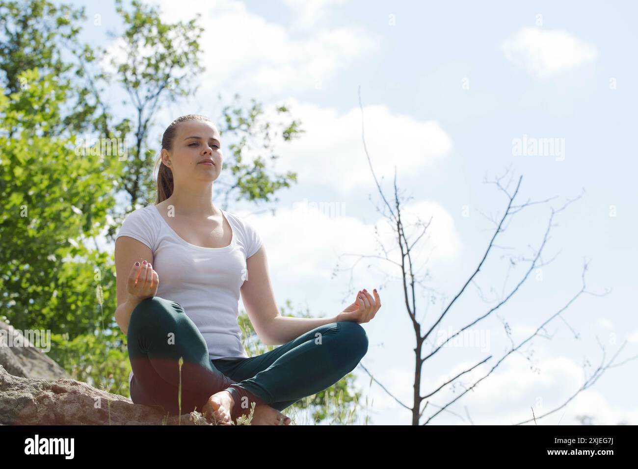 Healthy calm young woman meditating in nature with eyes closed, doing ...